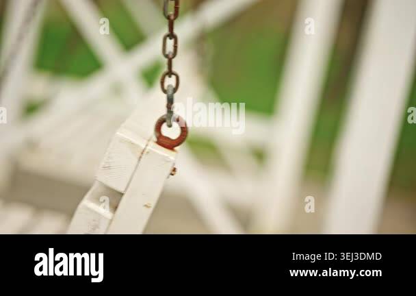 Extreme close up of a metal chain attached to a white wooden swing ...
