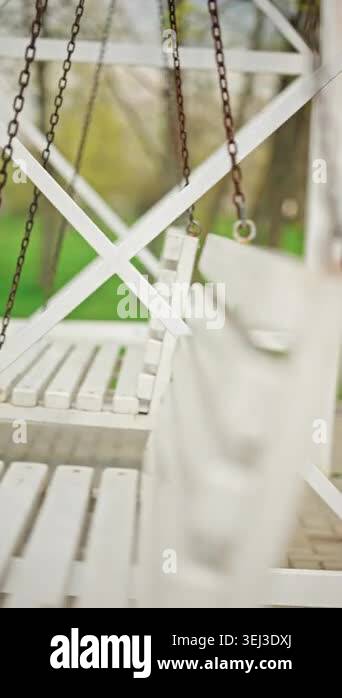 Extreme close up of a metal chain attached to a white wooden swing ...
