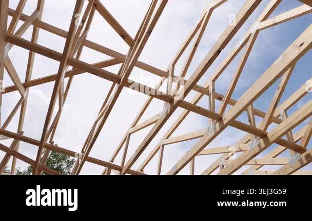 Workers construct wooden roof frame at construction site with outdoor ...