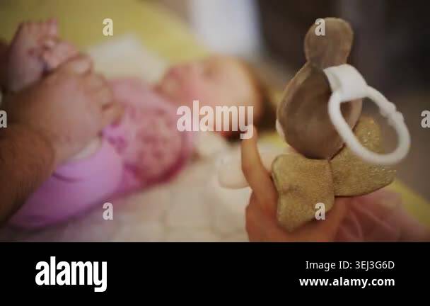 Close up of a parent holding a soft plush toy with a ring near a baby ...