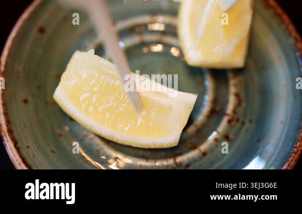 Slices of lemon placed on a small plate, with a wooden stick inserted ...