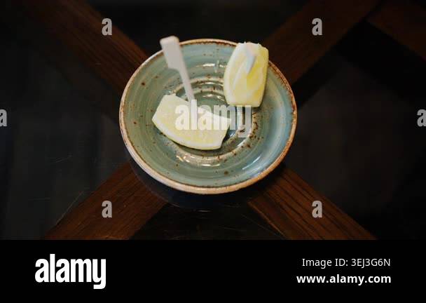 Slices of lemon placed on a small plate, with a wooden stick inserted ...