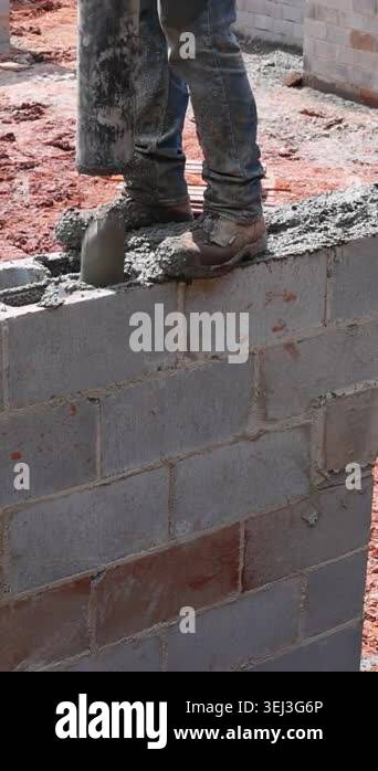Construction worker fills masonry block wall with wet concrete at ...