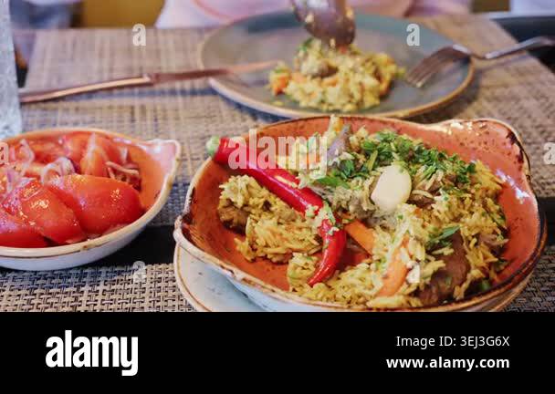 A plate of rice mixed with chunks of meat and vegetables, topped with ...