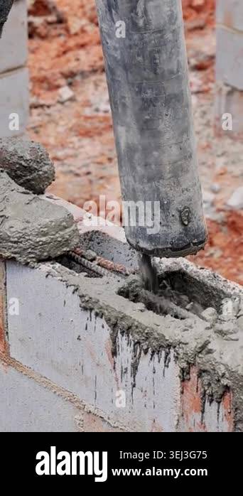 Construction worker operates concrete pump to compact fresh concrete on ...