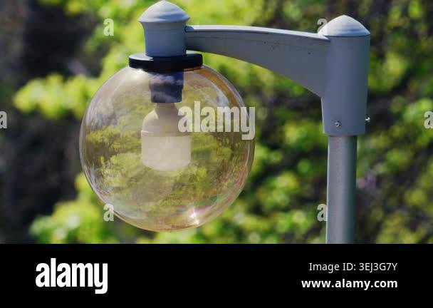 A large outdoor lamp with a visible filament is shown in close up. The ...