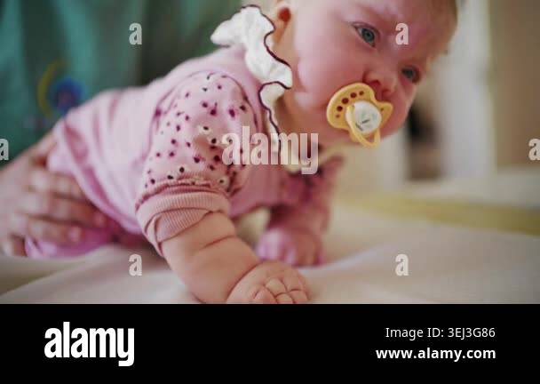 Baby lying relaxed on a soft surface while being gently touched by a ...