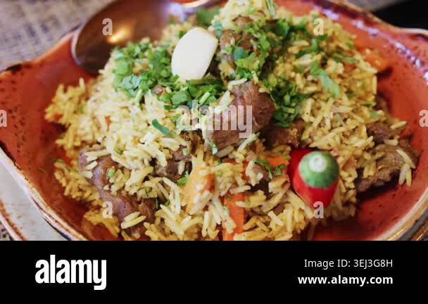 A plate of rice mixed with chunks of meat and vegetables, topped with ...