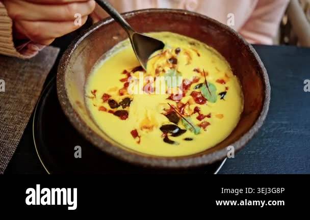 Close up of a spoon picking up creamy pumpkin soup served in a rustic ...