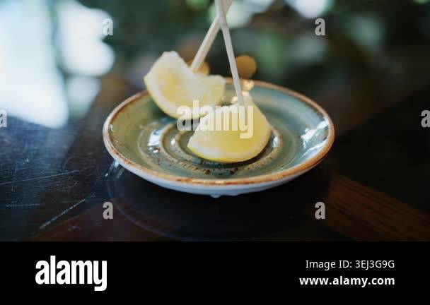 Slices of lemon placed on a small plate, with a wooden stick inserted ...