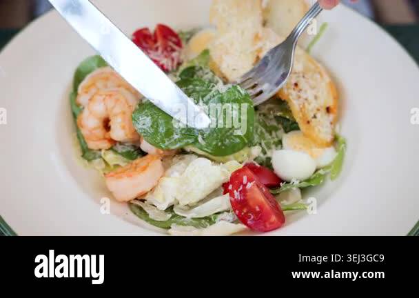 Close up of a fresh shrimp salad being cut and eaten with fork and ...