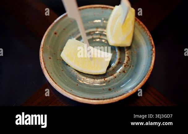 Slices of lemon placed on a small plate, with a wooden stick inserted ...