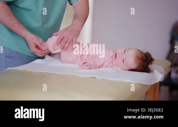 Baby lying on a padded treatment table while a caregiver gently moves ...