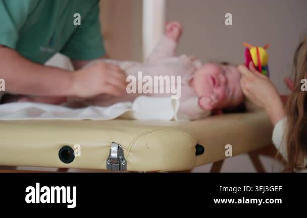 Infant wearing a light pink onesie with small dark heart patterns is ...