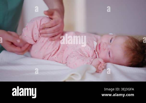 Close up of a baby lying on a treatment table while an adult gently ...