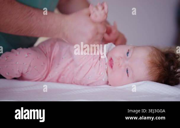 Baby lying on a padded treatment table while a caregiver gently moves ...