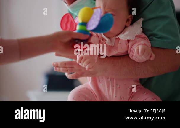 Healthcare professional wearing a medical mask gently supporting a baby ...