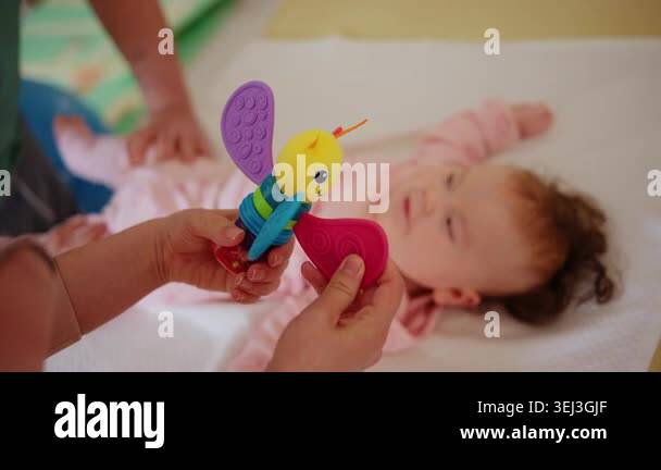Colorful sensory toy held in front of a baby during a pediatric therapy ...