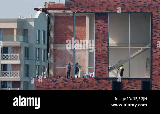 Workers inside a modern building under construction with exposed brick ...