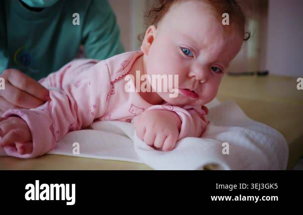 Healthcare professional wearing a medical mask gently supporting a baby ...