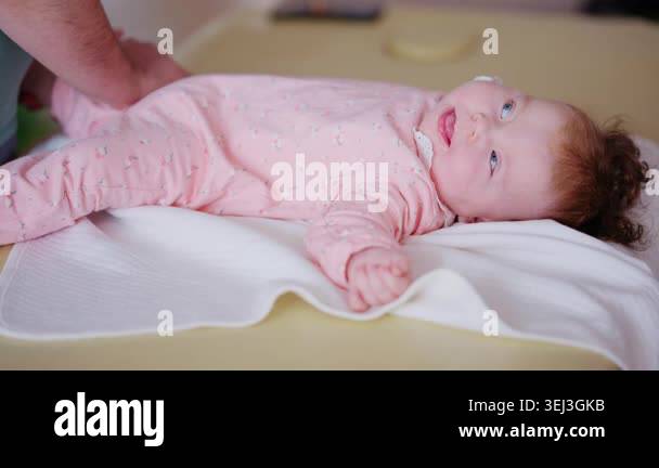 Close up of a baby lying on a treatment table while an adult gently ...