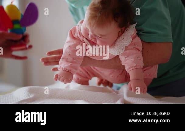 Healthcare professional wearing a medical mask gently supporting a baby ...