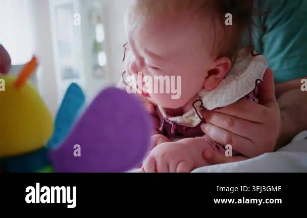 Baby being gently supported during tummy time while looking toward a ...