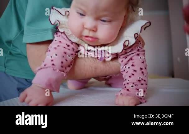 Baby being gently supported by an adult during a tummy time exercise on ...