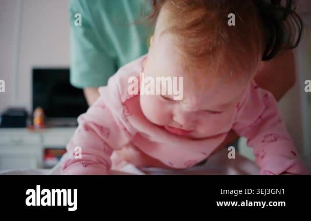 Close up of a baby being gently supported during tummy time on a padded ...