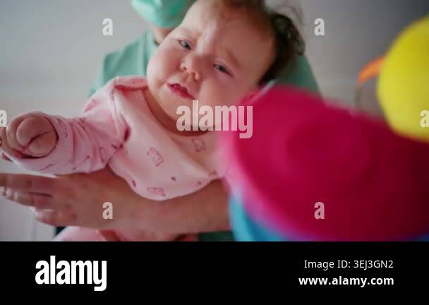 Close up of a baby being gently supported during tummy time on a padded ...