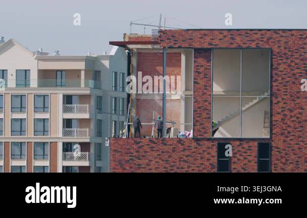 Workers inside a modern building under construction with exposed brick ...