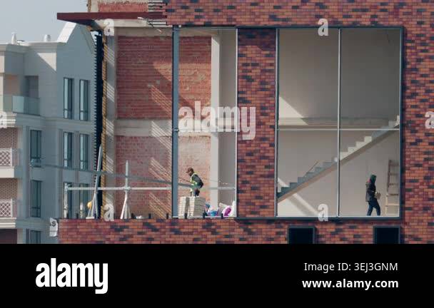 Workers inside a modern building under construction with exposed brick ...
