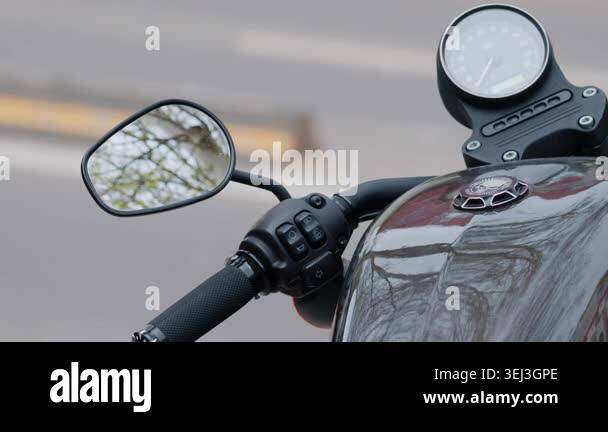 Close up view of a motorcycle mirror, handlebar controls, speedometer ...