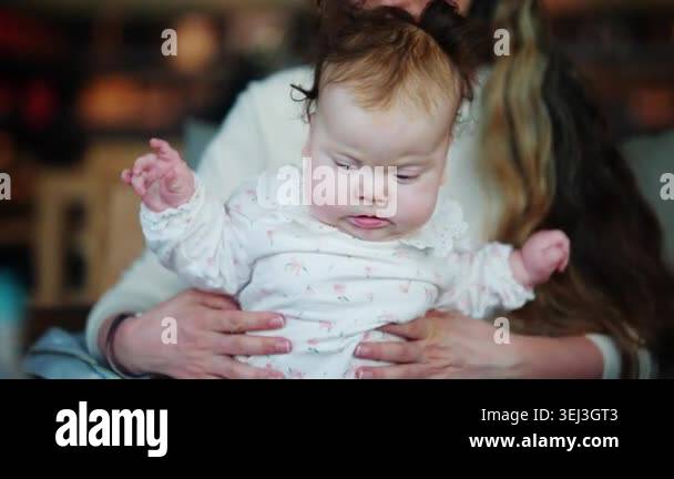 Close up of a baby being gently held by an adult indoors, with soft ...