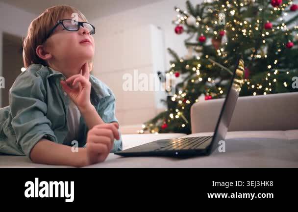 In a brightly lit room, a boy wearing glasses is lying on a sofa in the ...