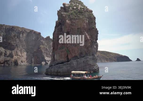 Dramatic volcanic basalt sea stack rising from calm blue Tyrrhenian Sea ...