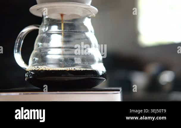 Cold brew coffee steeping in a glass pitcher with paper filter and ...