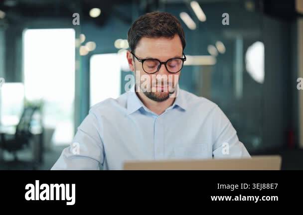 Close-up portrait of cheerful male manager holding glasses in hand and ...
