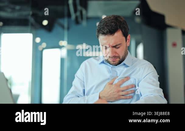Overworked businessman sitting at desk with laptop and holding hand on ...