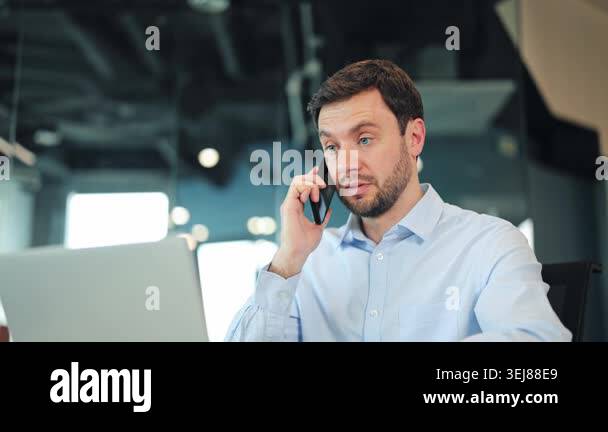 Focused male creator or digital nomad speaking on mobile phone and ...