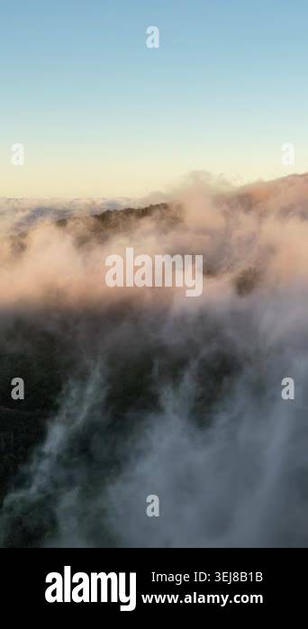 Golden light shines on a vast sea of clouds covering the mountain ...