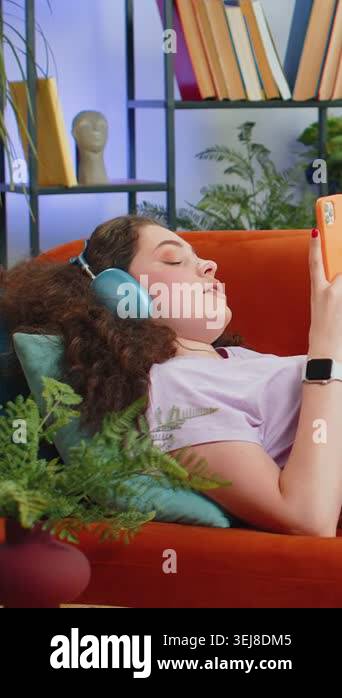 Portrait of happy overjoyed woman in wireless headphones relaxing lying ...