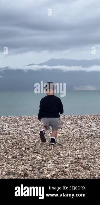 Small child walking on pebble beach by a sea Stock Video Footage - Alamy