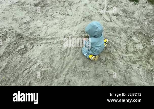 Overhead toddler in blue hooded jacket sitting on sand copy space Stock ...