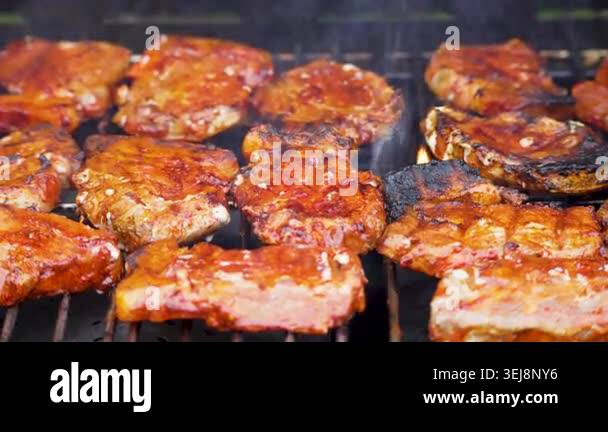 Marinated pork steaks sizzle on a hot barbecue grill. Smoke and charred ...