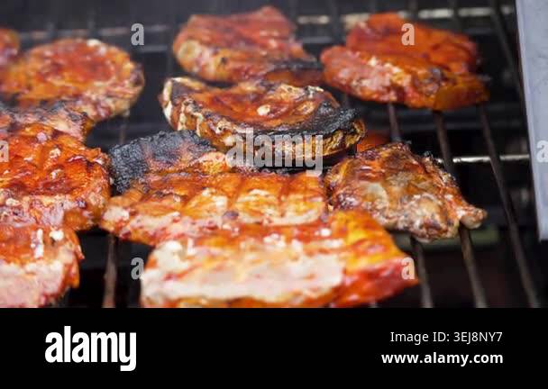 Marinated pork steaks grill over bright flames. Smoke and caramelized ...