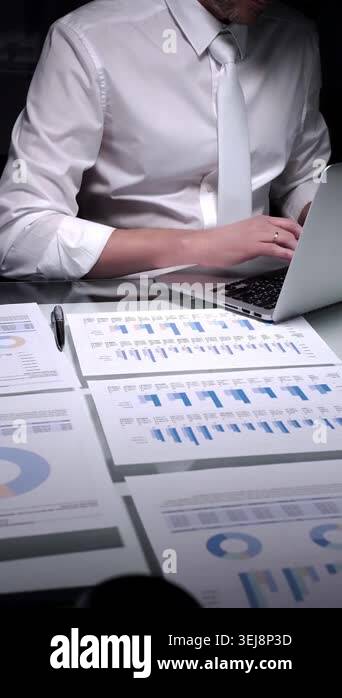 Businessman studying financial report data with laptop and charts ...