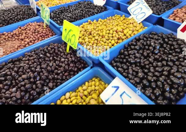 Many types of olives are on display at a market with price tags Stock ...