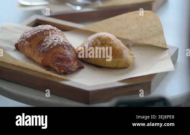 Two baked pastries rest on parchment paper at a cafe table Stock Video ...