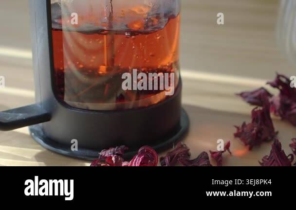 People brew hibiscus tea with dried flowers using a glass pot and hot ...